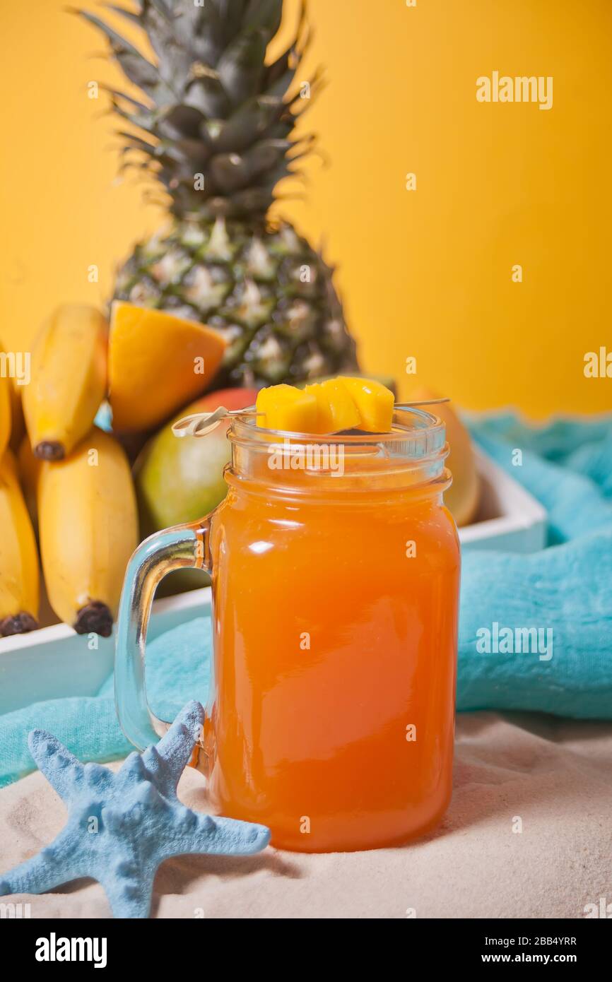 Glass of tropical exotic multifruit juice on the sand with fruits on ...