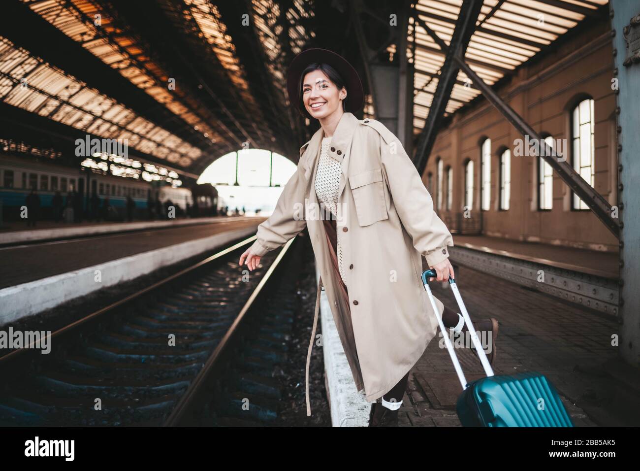 Cheerful young lady traveler is waiting for her train at the train ...