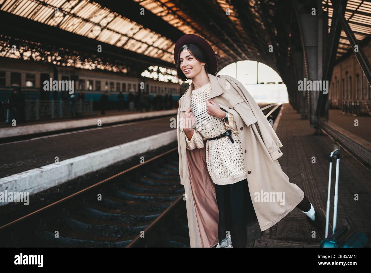 Cheerful young lady traveler is waiting for her train at the train ...