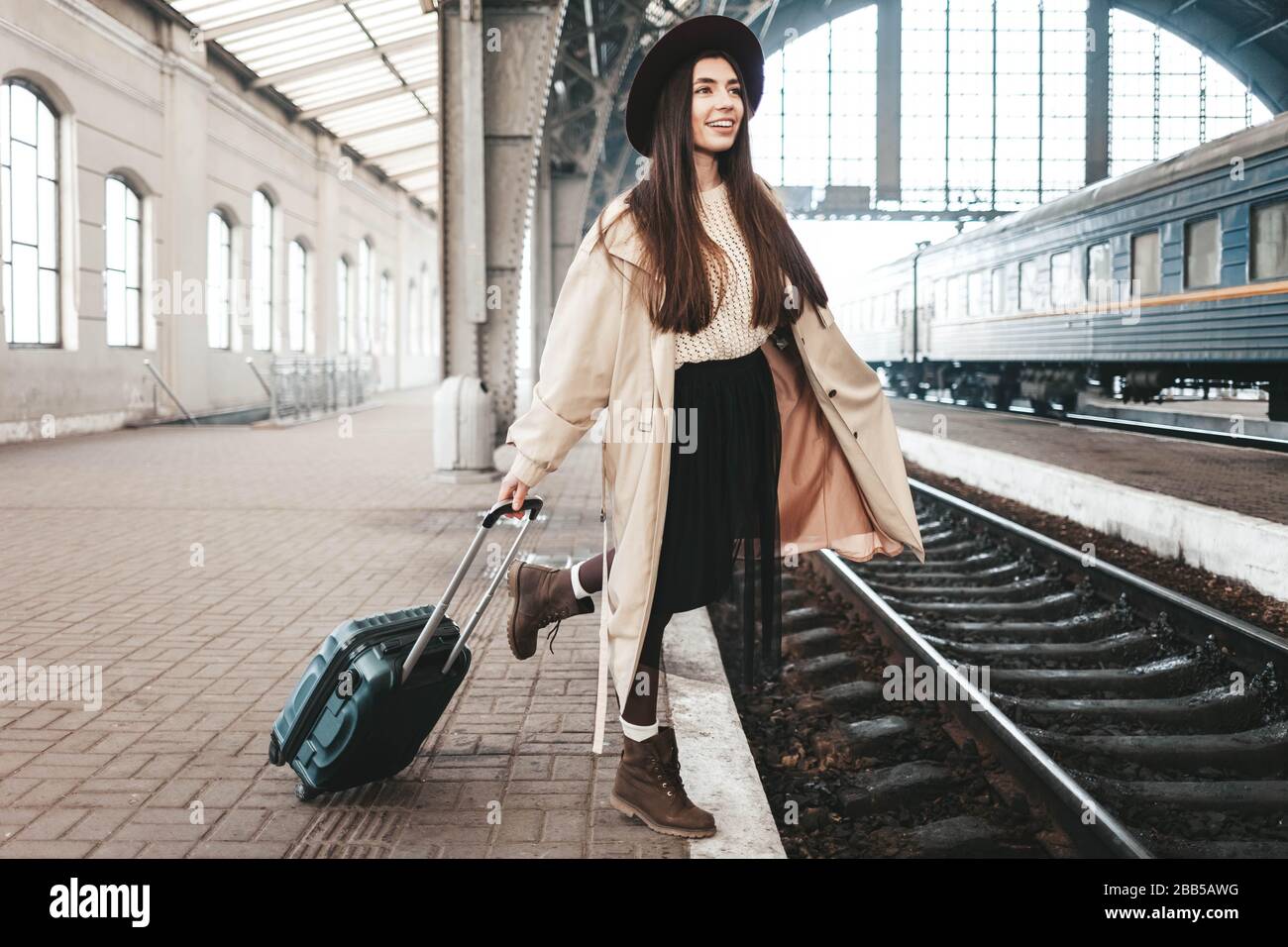Cheerful young lady traveler is waiting for her train at the train ...