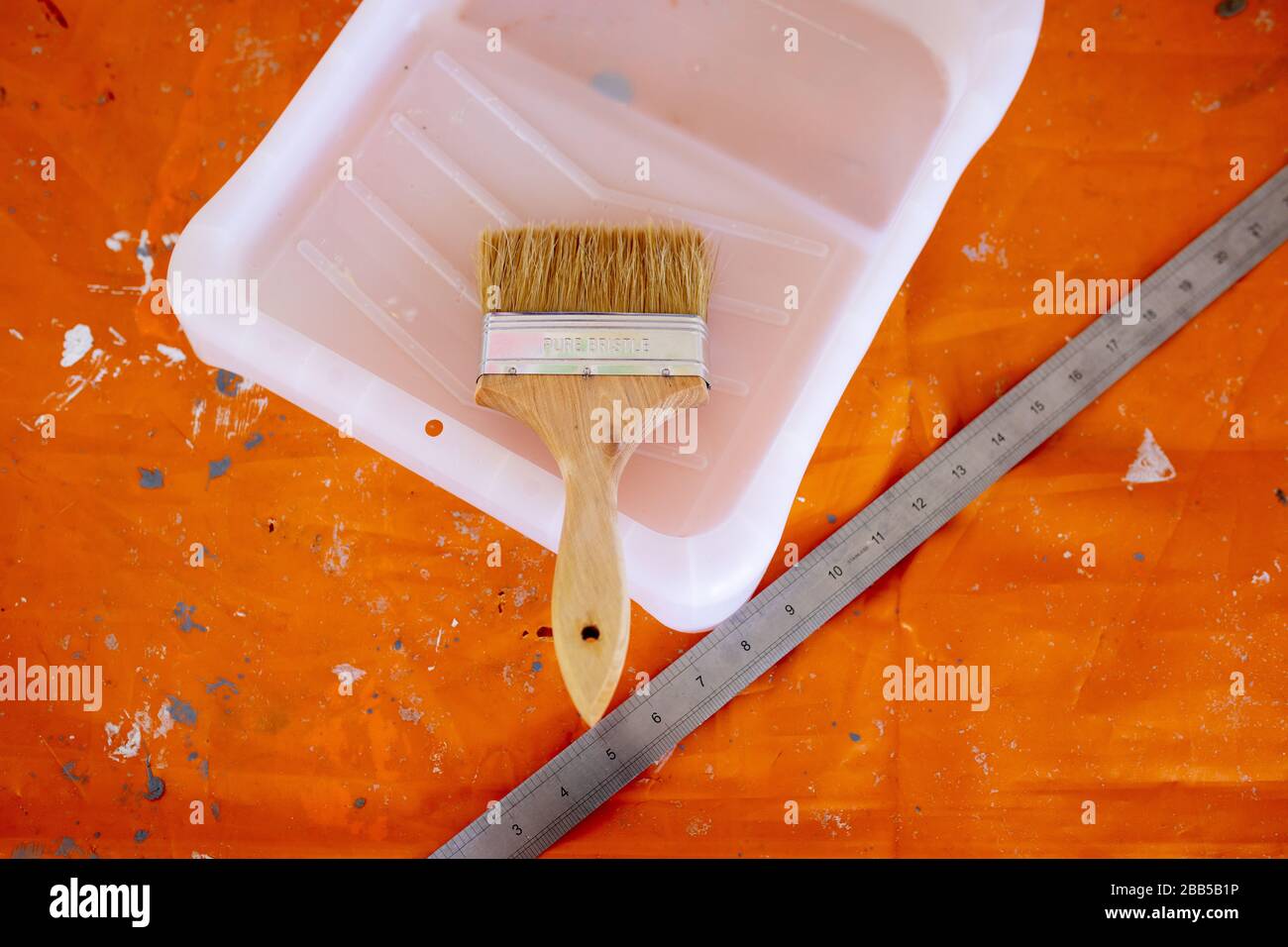 Paint brush, paint bucket and ruler lay on a table Stock Photo - Alamy