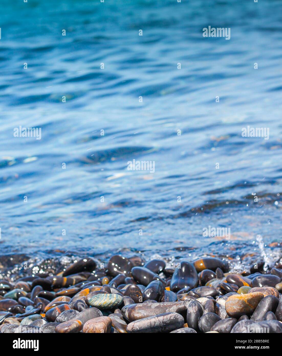 Beautiful black-toned rocks are rounded, curved along the beach, where ...