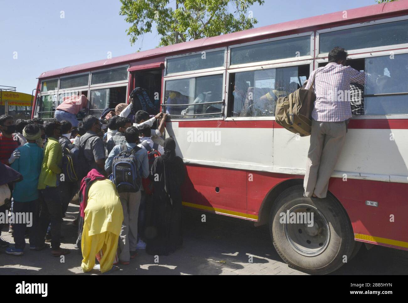Unemployed migrant workers desperate to return get into a bus through a ...