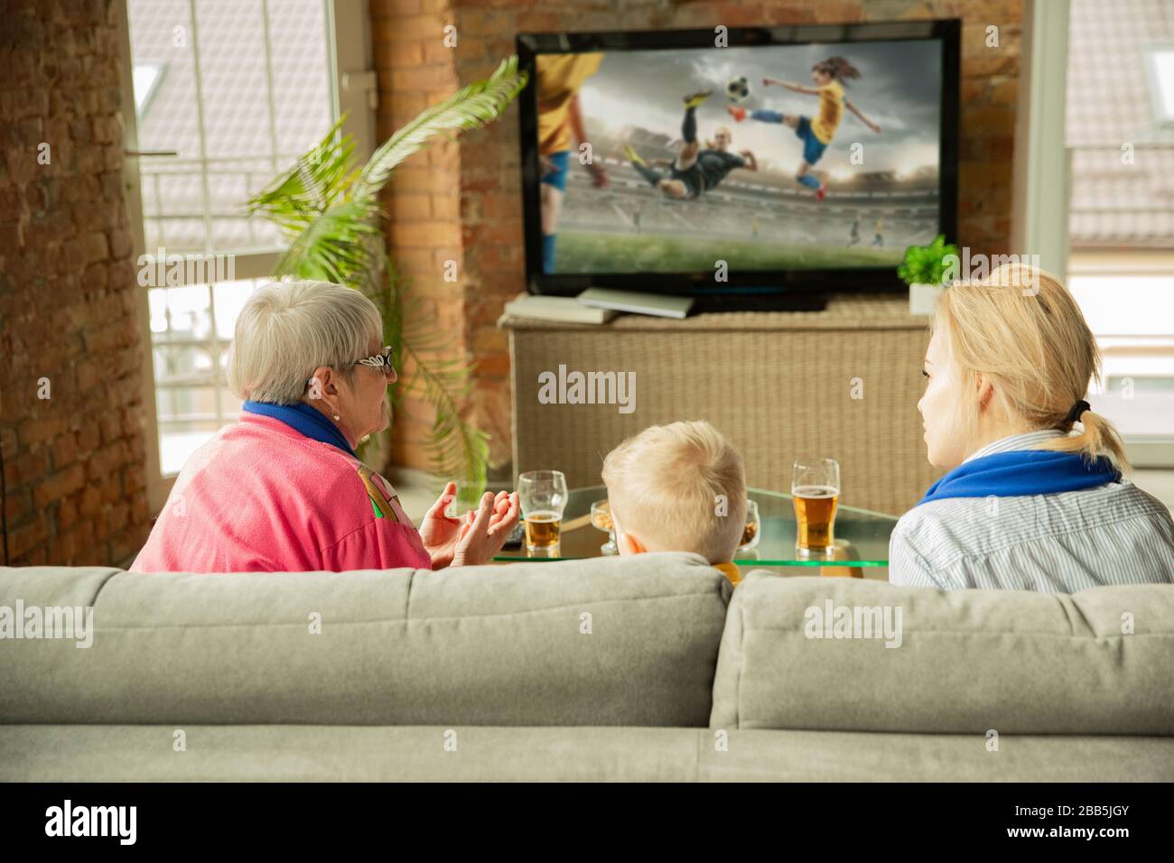 Excited family watching football, sport match at home. Grandma, mother ...
