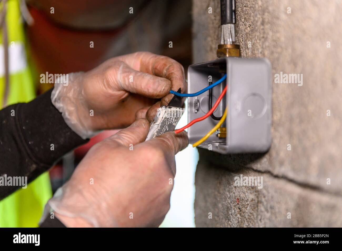 Male electrician cutting wire for socket plug on garage wall Stock ...