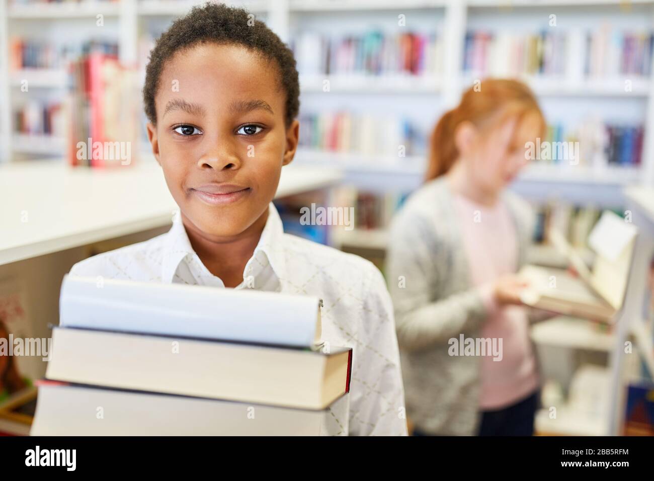 African student in elementary school carries books from the library ...