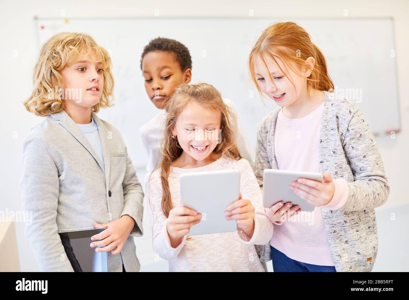 Happy group of kids in a primary school classroom with tablet computer ...