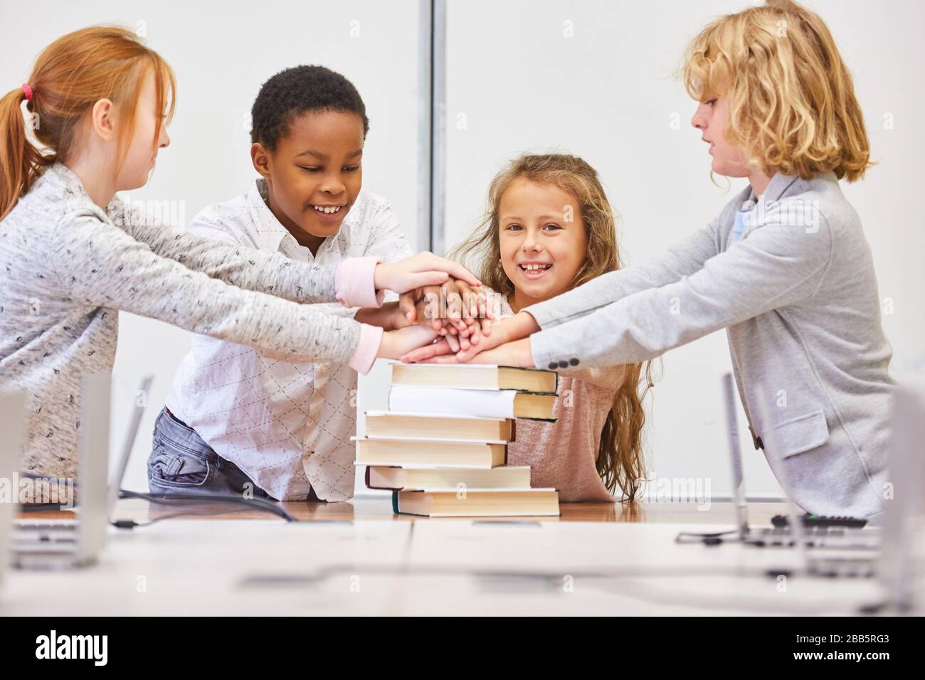 Group of children in elementary school stack hands for motivation in ...