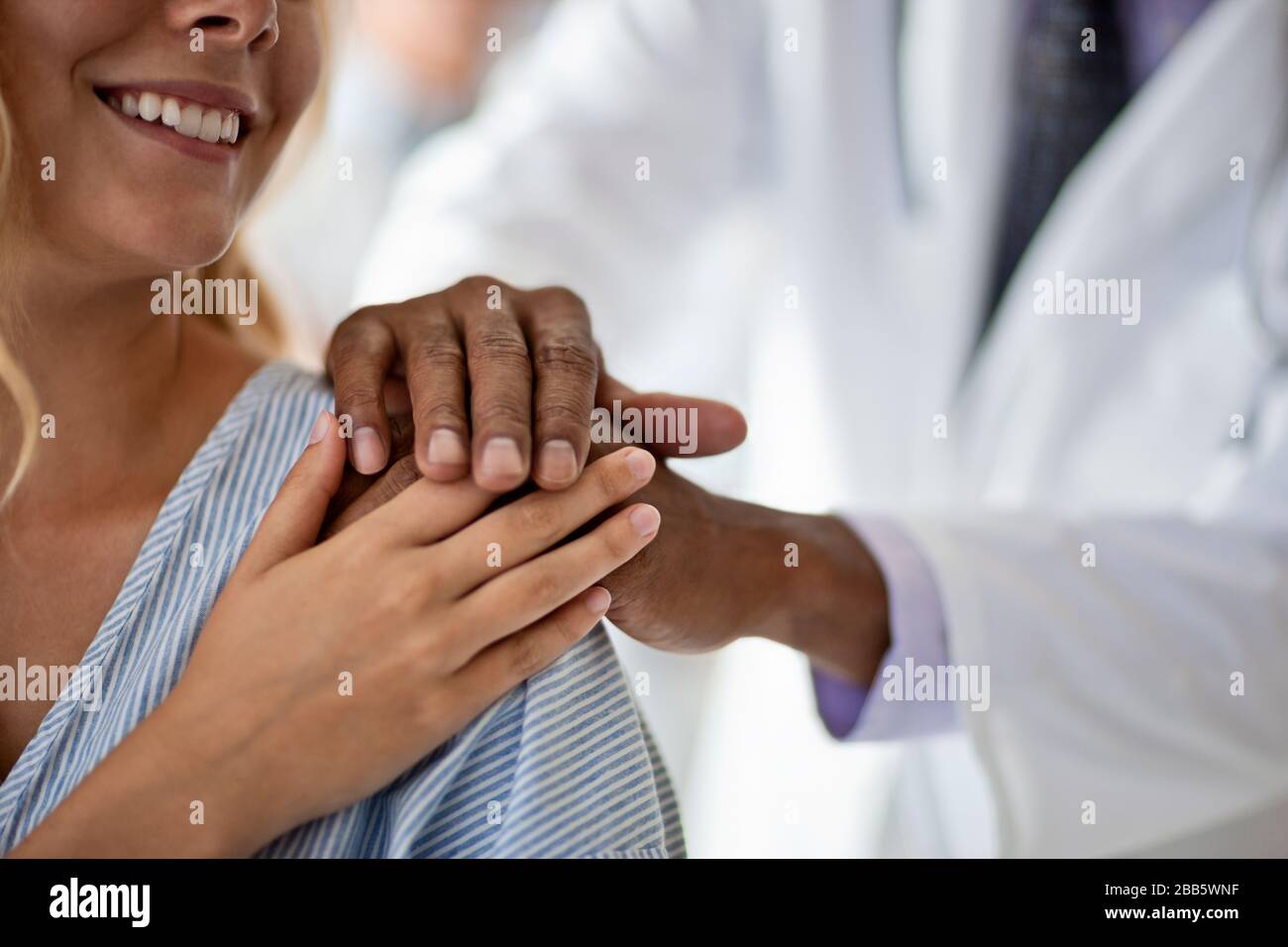 Female Hospital Patient Smiling As She Touches Her Doctors Comforting