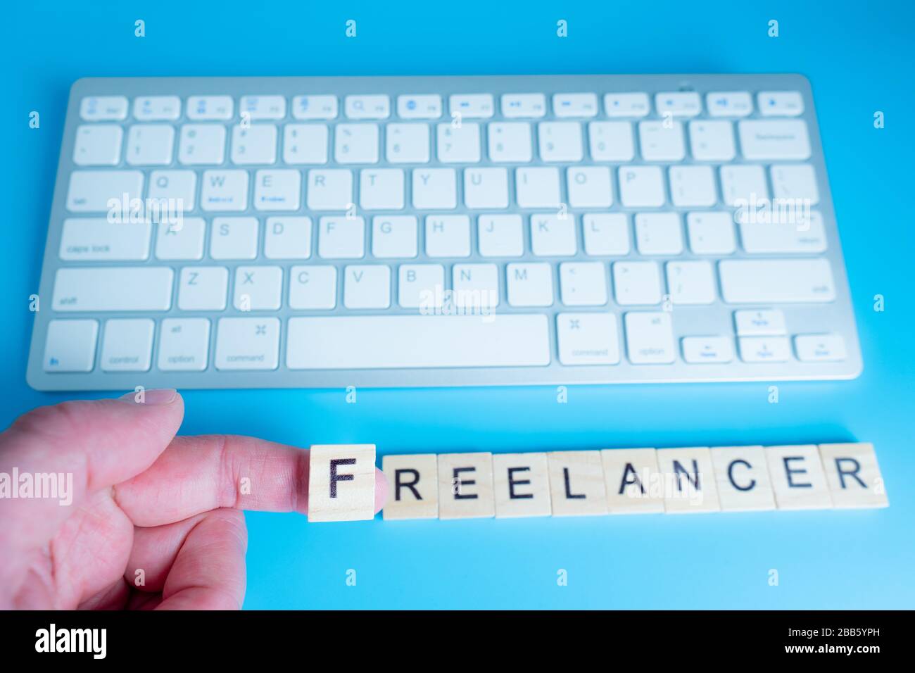 Keyboard and Freelancer signr on a blue background. Concept workspace ...