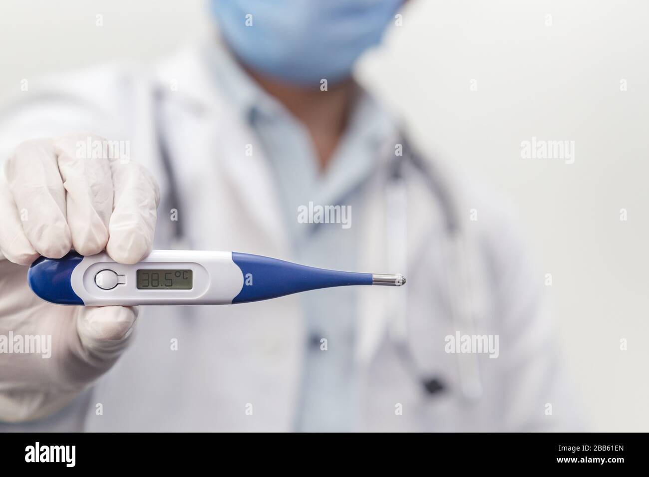 Doctor wearing stethoscope holds digital medical thermometer to measure ...
