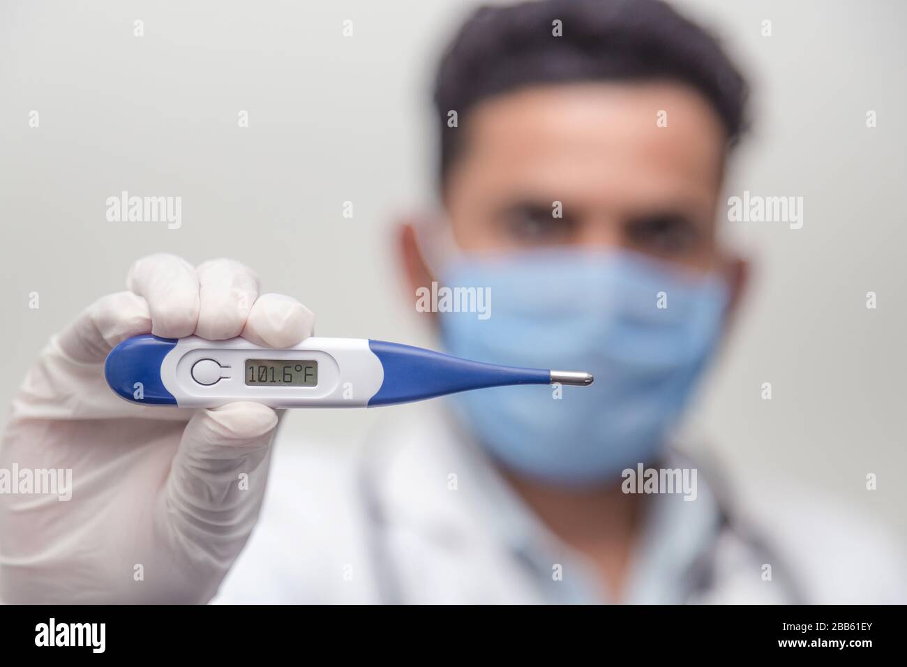 Doctor wearing stethoscope holds digital medical thermometer to measure ...