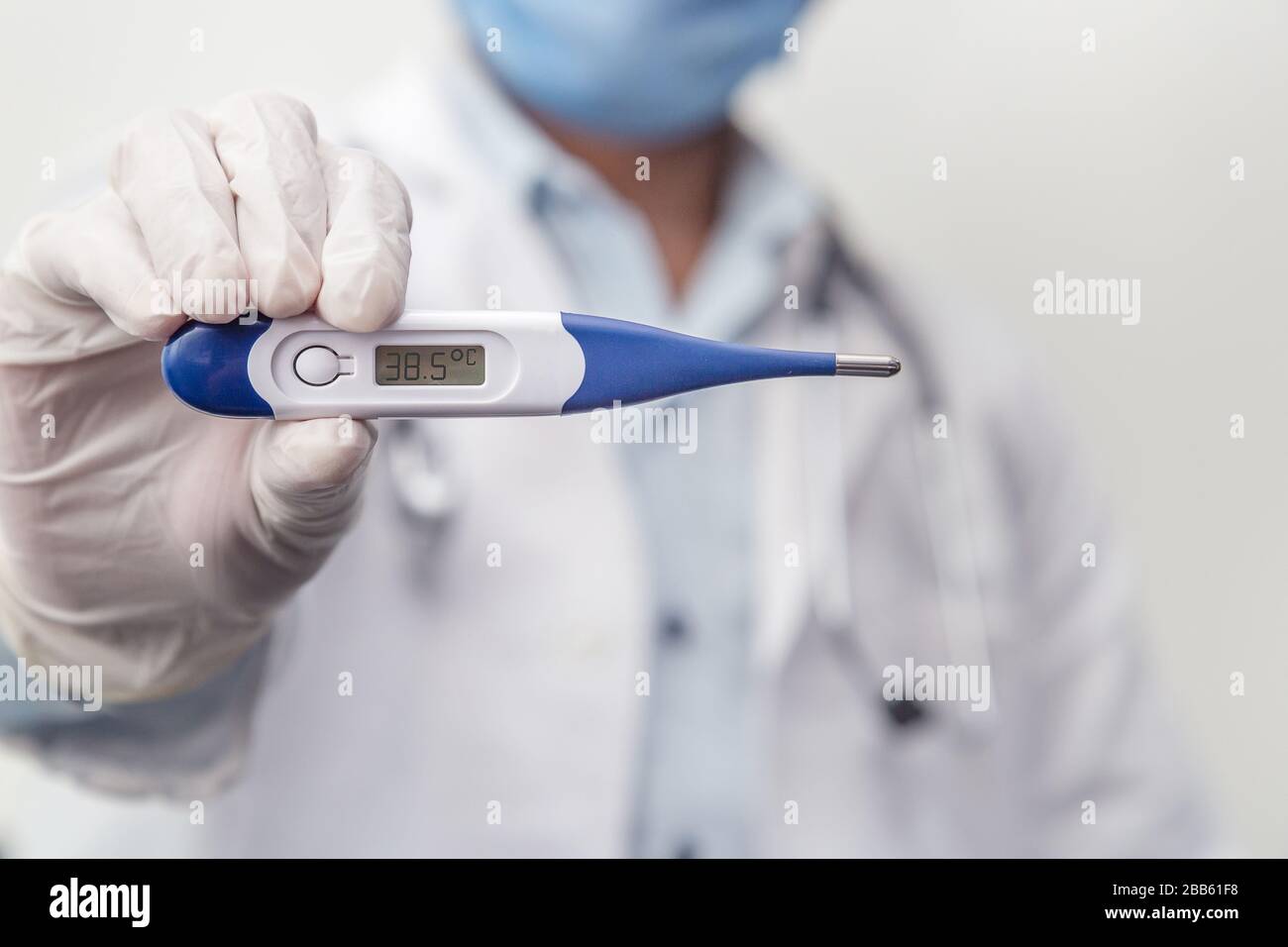 Doctor wearing stethoscope holds digital medical thermometer to measure ...