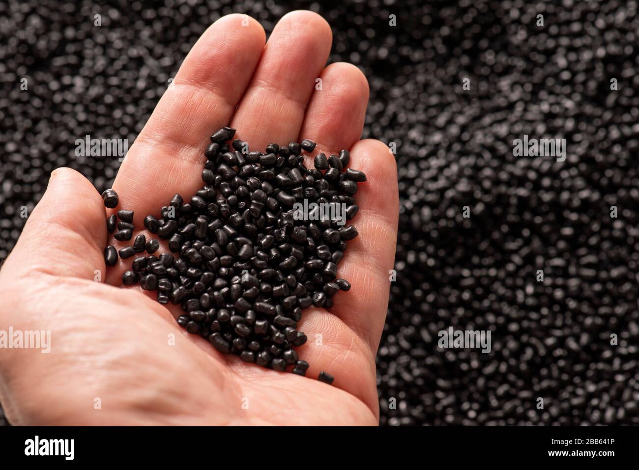 Granular recycled black plastic in hand Stock Photo - Alamy