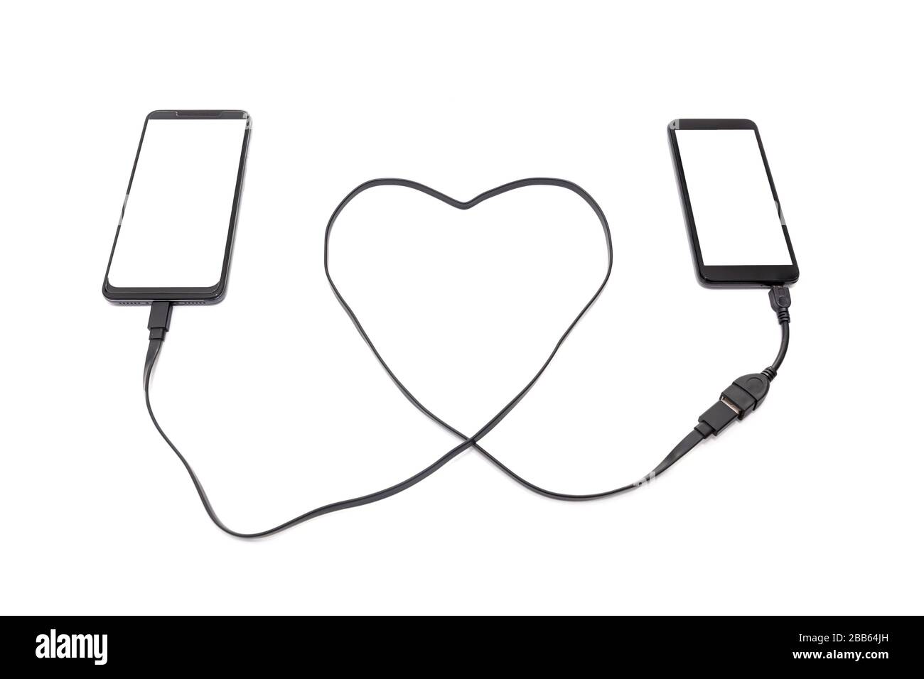 Hand connecting two smartphones with a heart shaped USB cable. Long ...