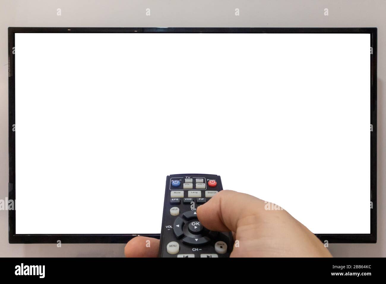 Person pointing a TV remote and pressing buttons in front of a TV with ...