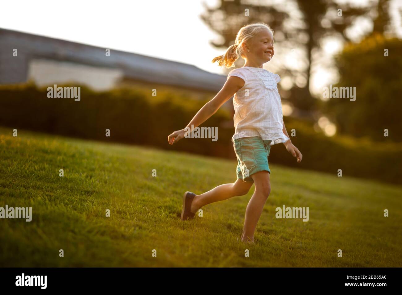 Young girl skipping across a green lawn Stock Photo - Alamy