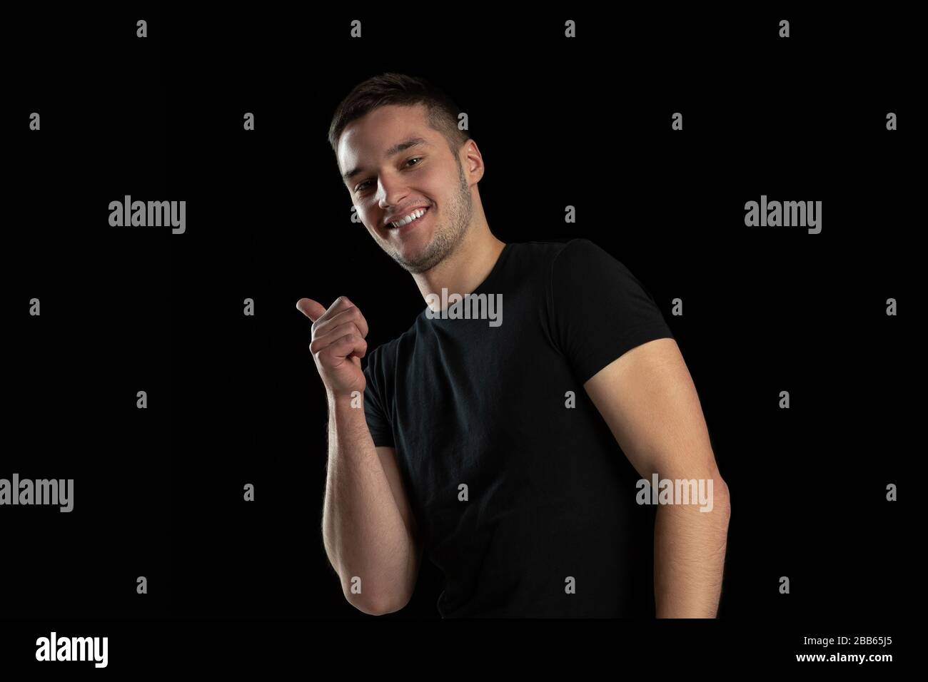 Pointing, smiling. Monochrome portrait of young caucasian man isolated ...