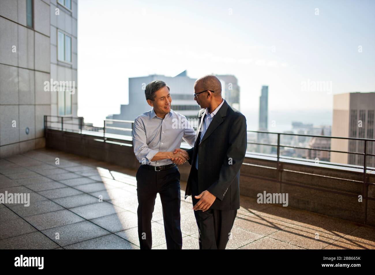 Businessmen shaking hands on balcony Stock Photo - Alamy