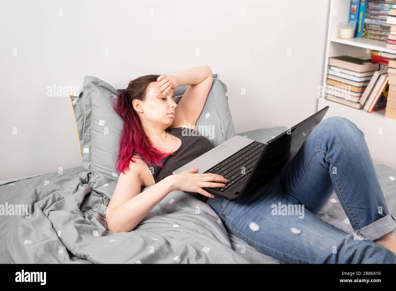 Concept - work from home, self-isolation. Young girl lies in bed ...