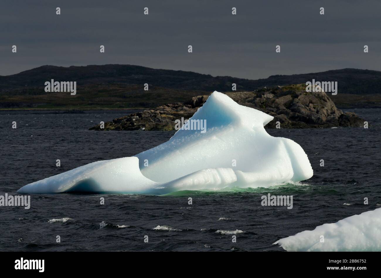 Bright white iceberg on dark water and rock background Stock Photo - Alamy