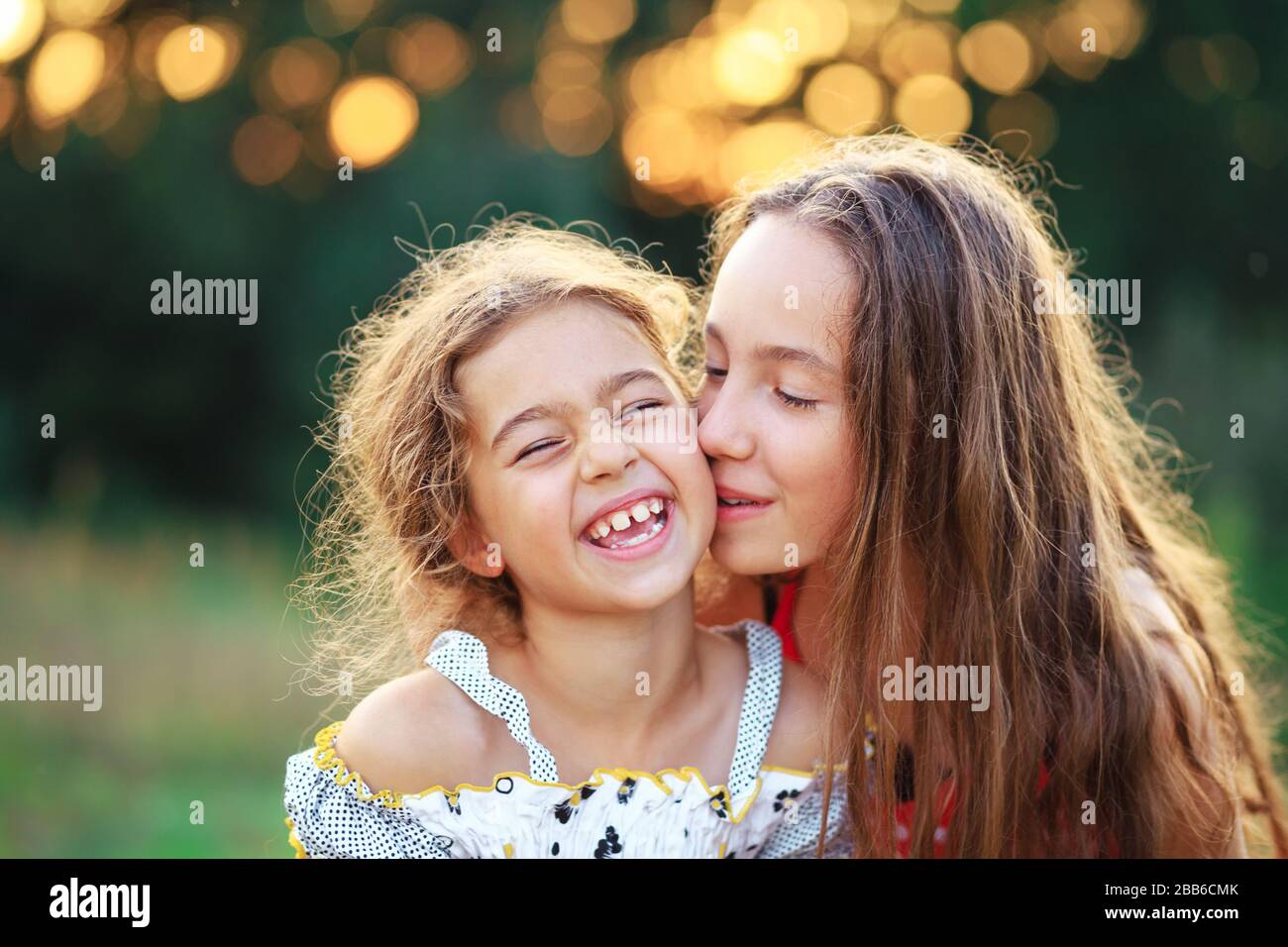 Two Cute little girls hugging and laughing at the countryside. Happy kids spending time outdoors ...