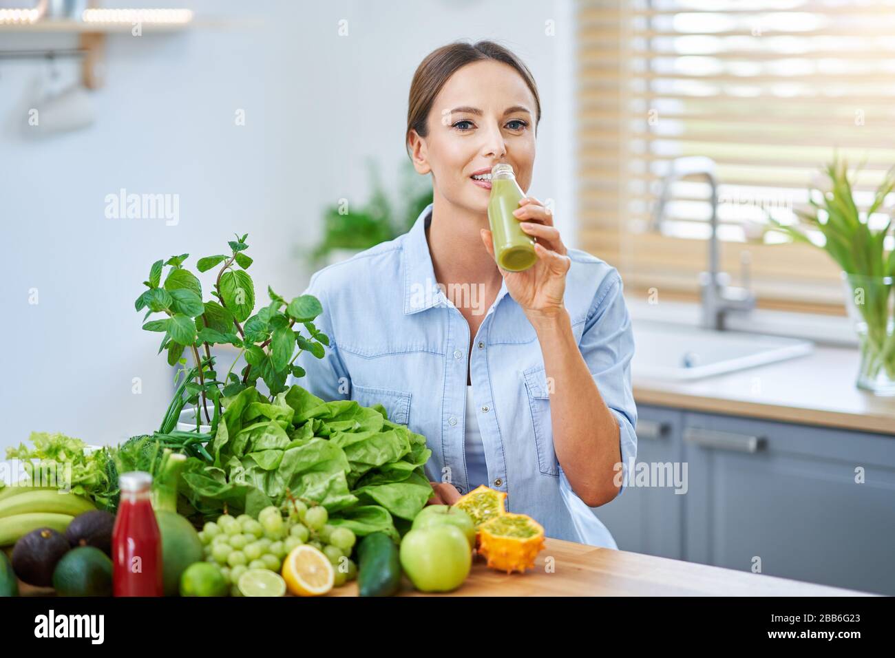 Healthy adult woman with green food in the kitchen Stock Photo - Alamy