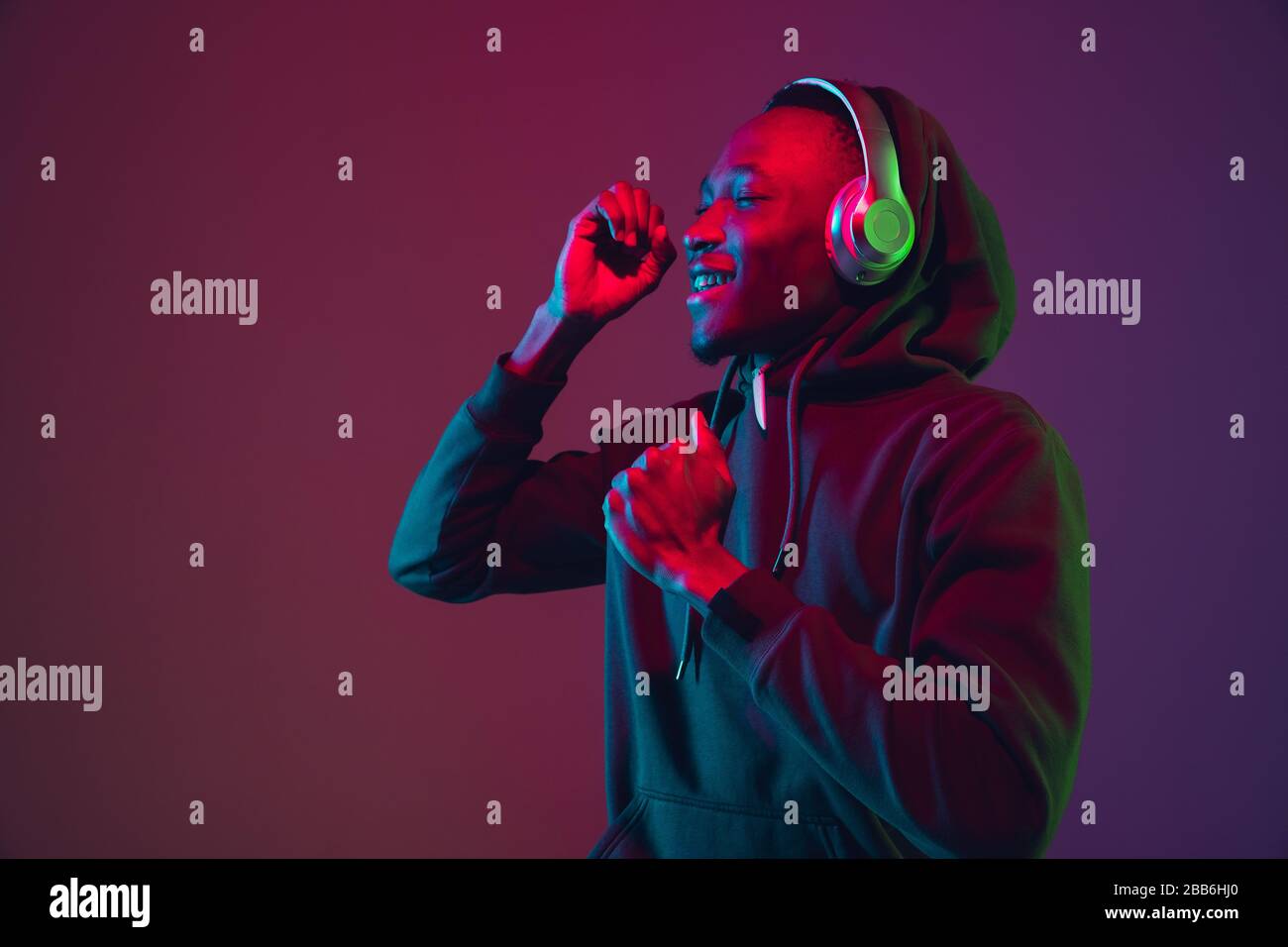 African-american man's portrait with headphones on gradient studio ...