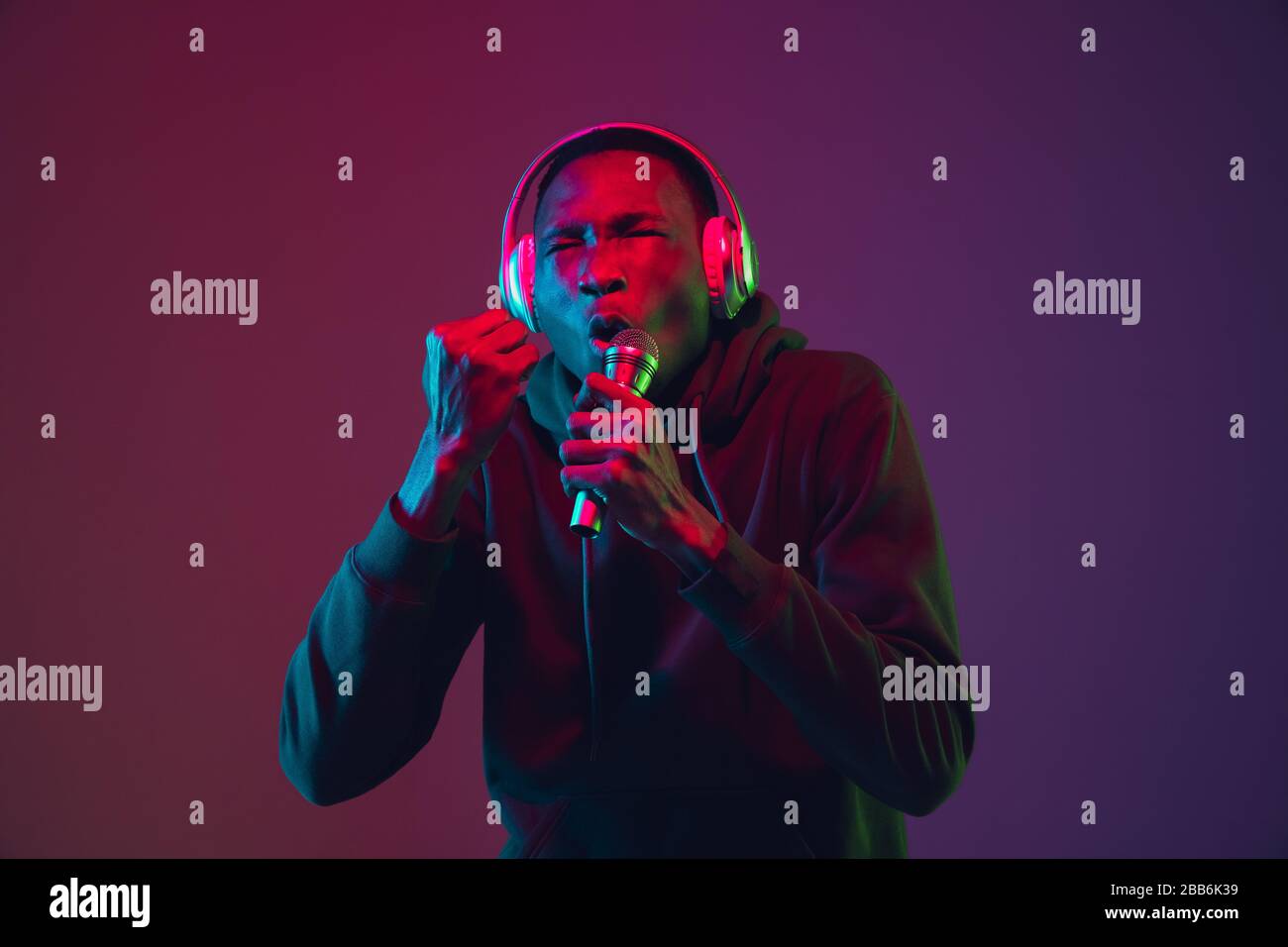 African-american man's portrait with headphones on gradient studio ...