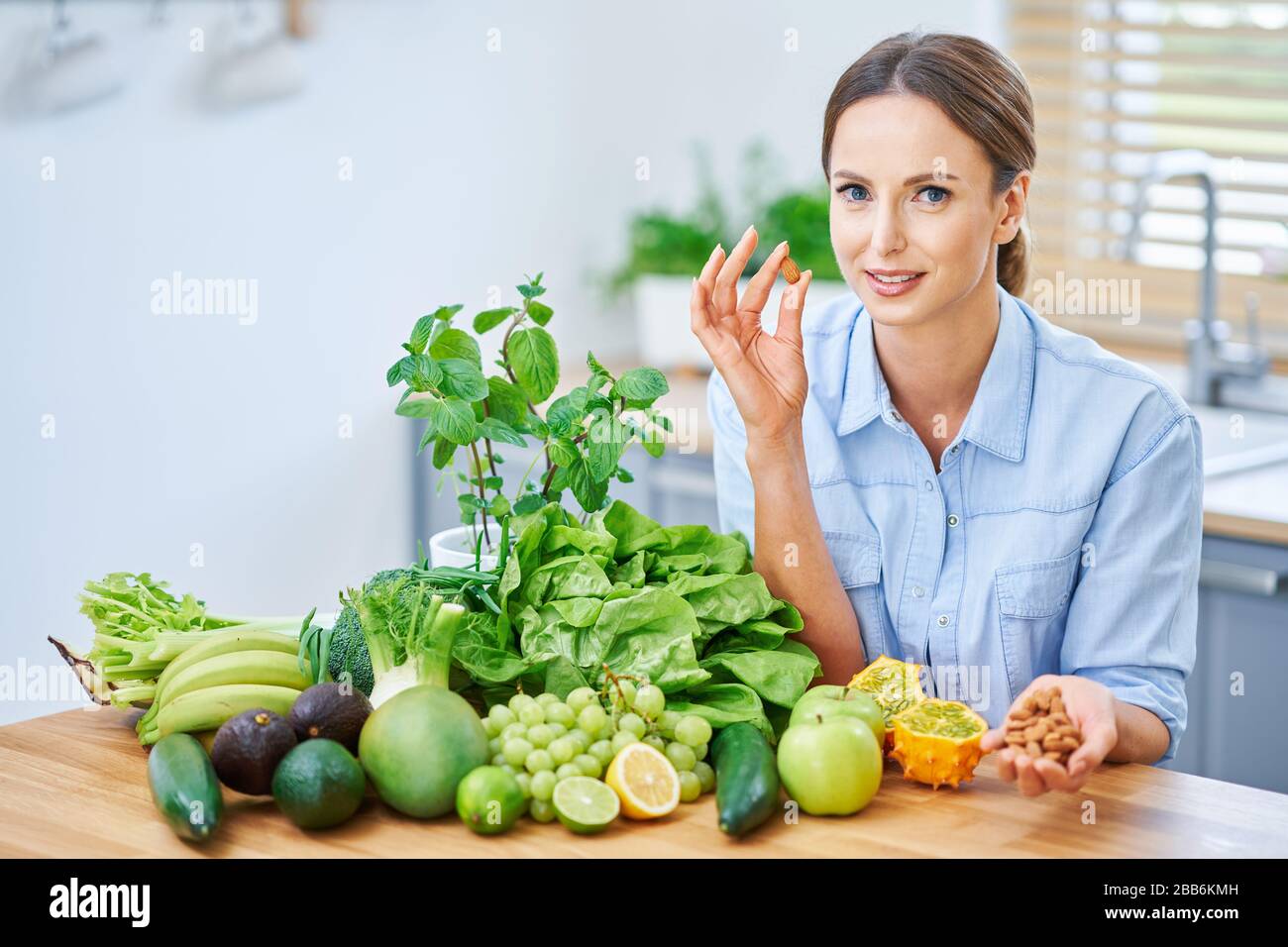 Healthy adult woman with green food in the kitchen Stock Photo - Alamy