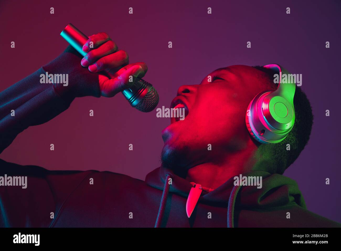 African-american man's portrait with headphones on gradient studio ...