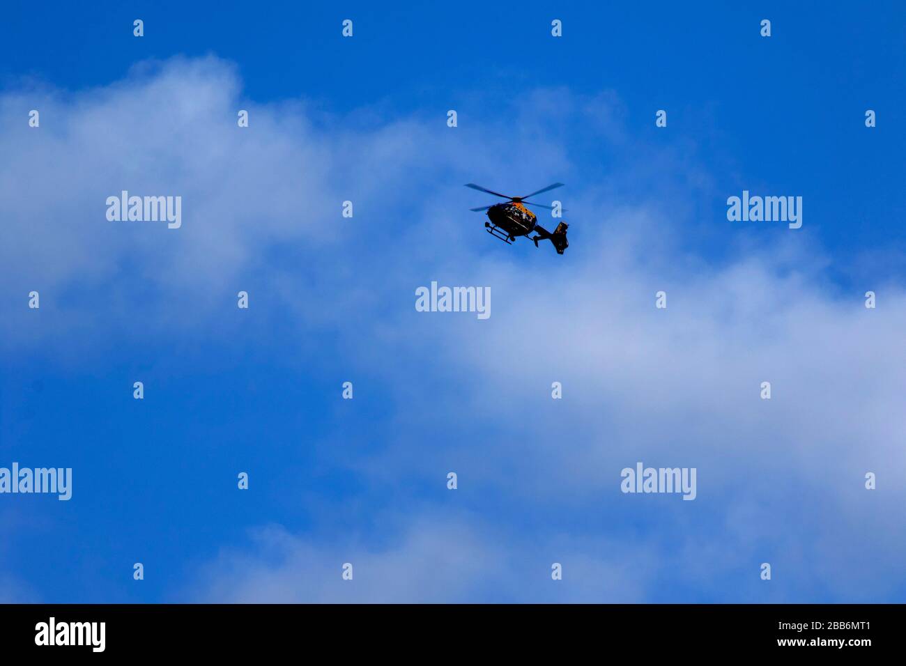 Police helicopter hovering over London with a blue sky and white cloud ...