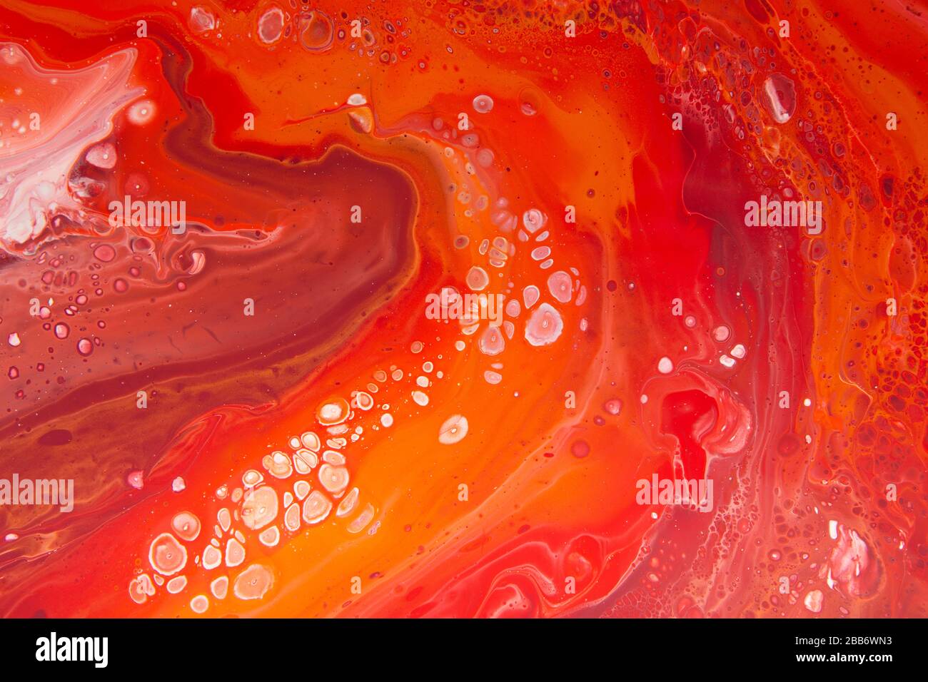 Vibrant red colour stains with white spots of liquid acrylic colors ...