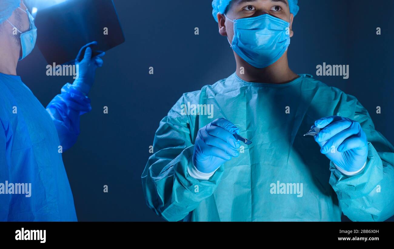 Portrait of two surgeons in sterile gowns, hats and masks. One surgeon ...