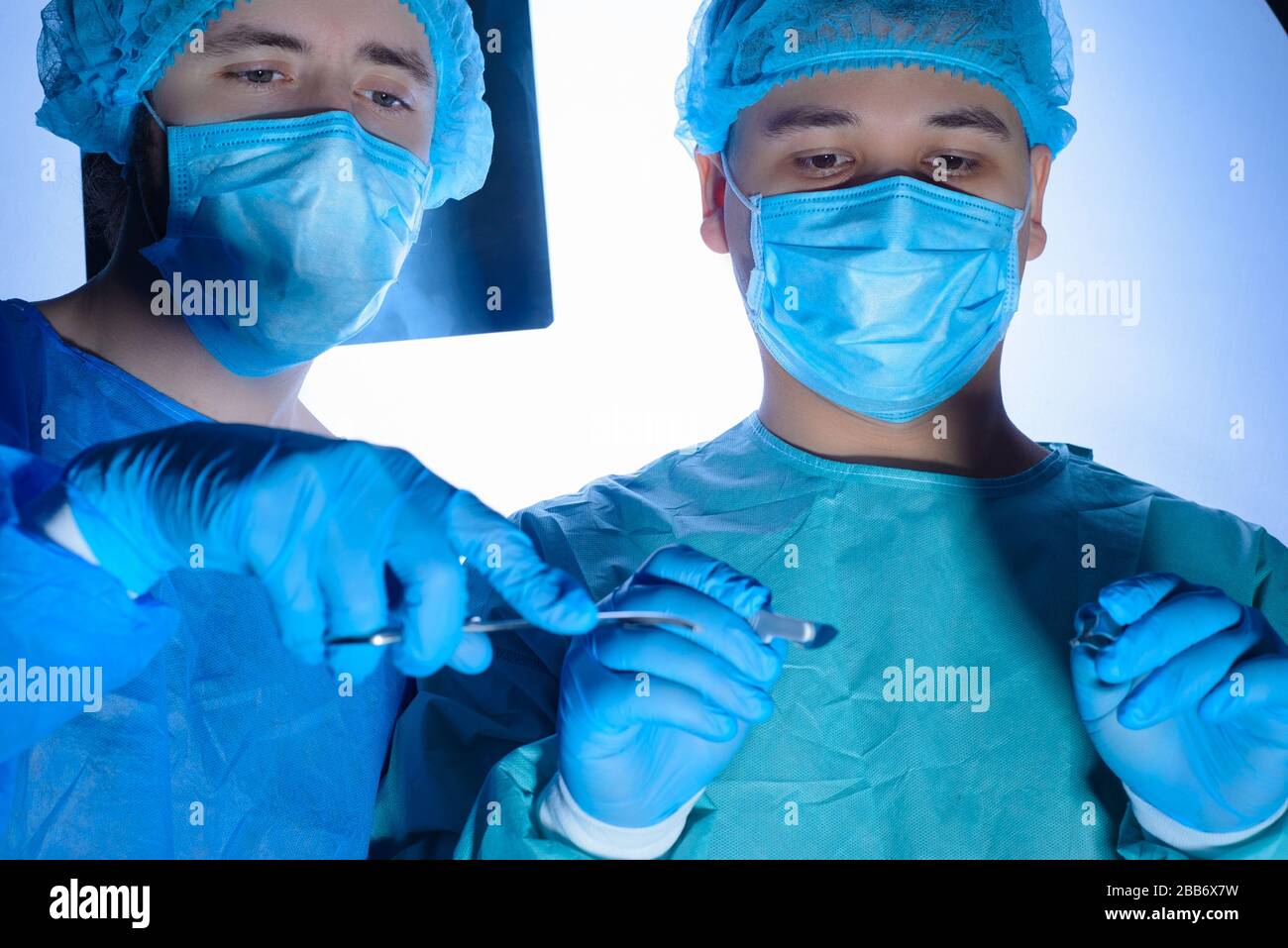 Portrait of two surgeons in sterile gowns, hats and masks. One surgeon ...