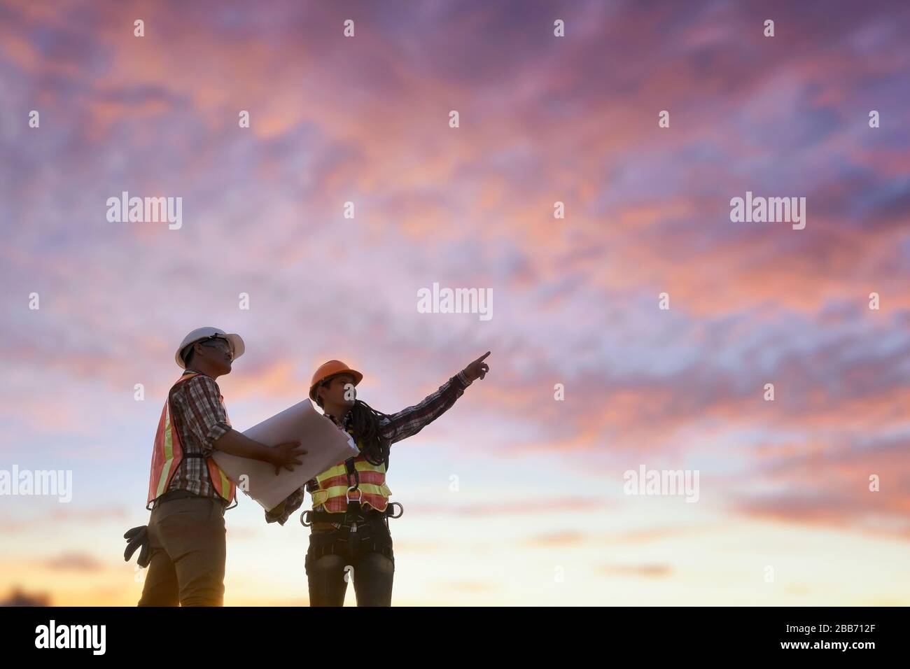 Two Construction workers on a construction site looking at plans ...