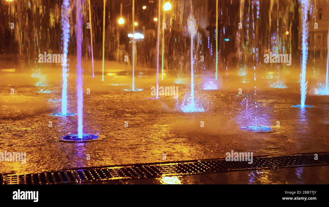 Splashes of colorful fountain. Water illuminated in diverse colors ...