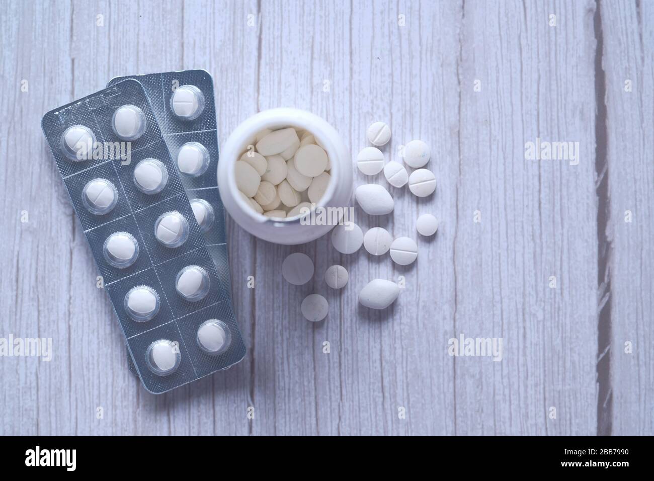 top view of white pills and container on table Stock Photo - Alamy