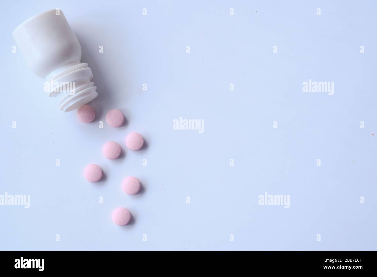 pink color pills spilling on white background, top view Stock Photo - Alamy