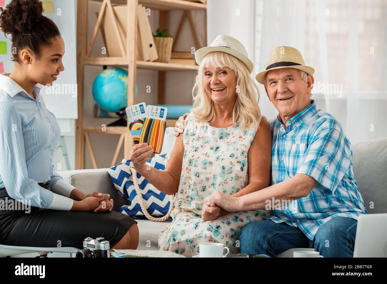 Travel agent at office with senior clients in beach hats cheerful ...