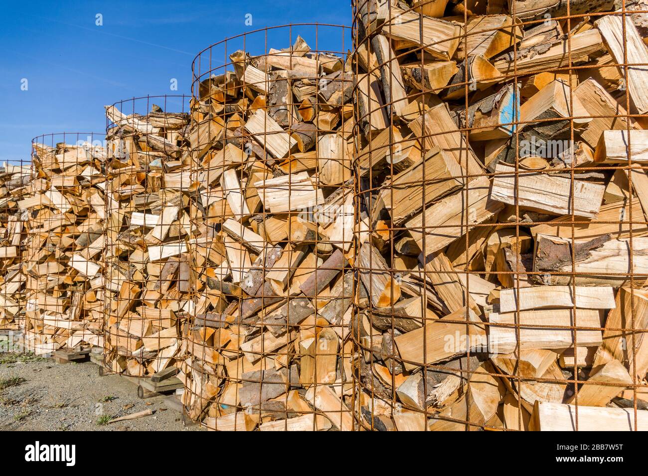 Chopped firewood Log stored in a round container of welded wire mesh ...