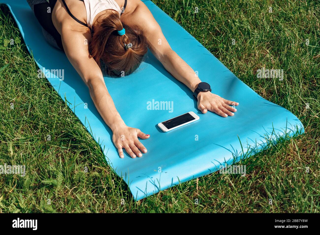 Healthy Lifestyle. Young woman outdoors sitting on yoga mat leaning ...