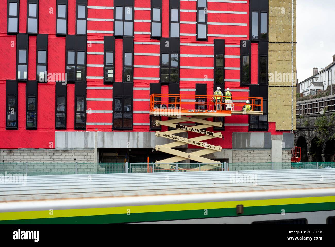 Builders on a cherry picker or boom platform at the Horgan's Quay red ...
