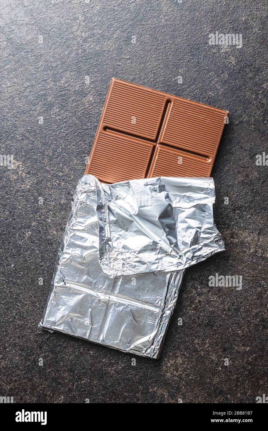 Wrapped chocolate bar in aluminum foil on black table. Top view Stock ...