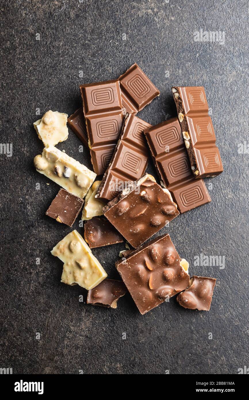 Milk chocolate bars. Dark and white nut chocolate on black table. Top ...