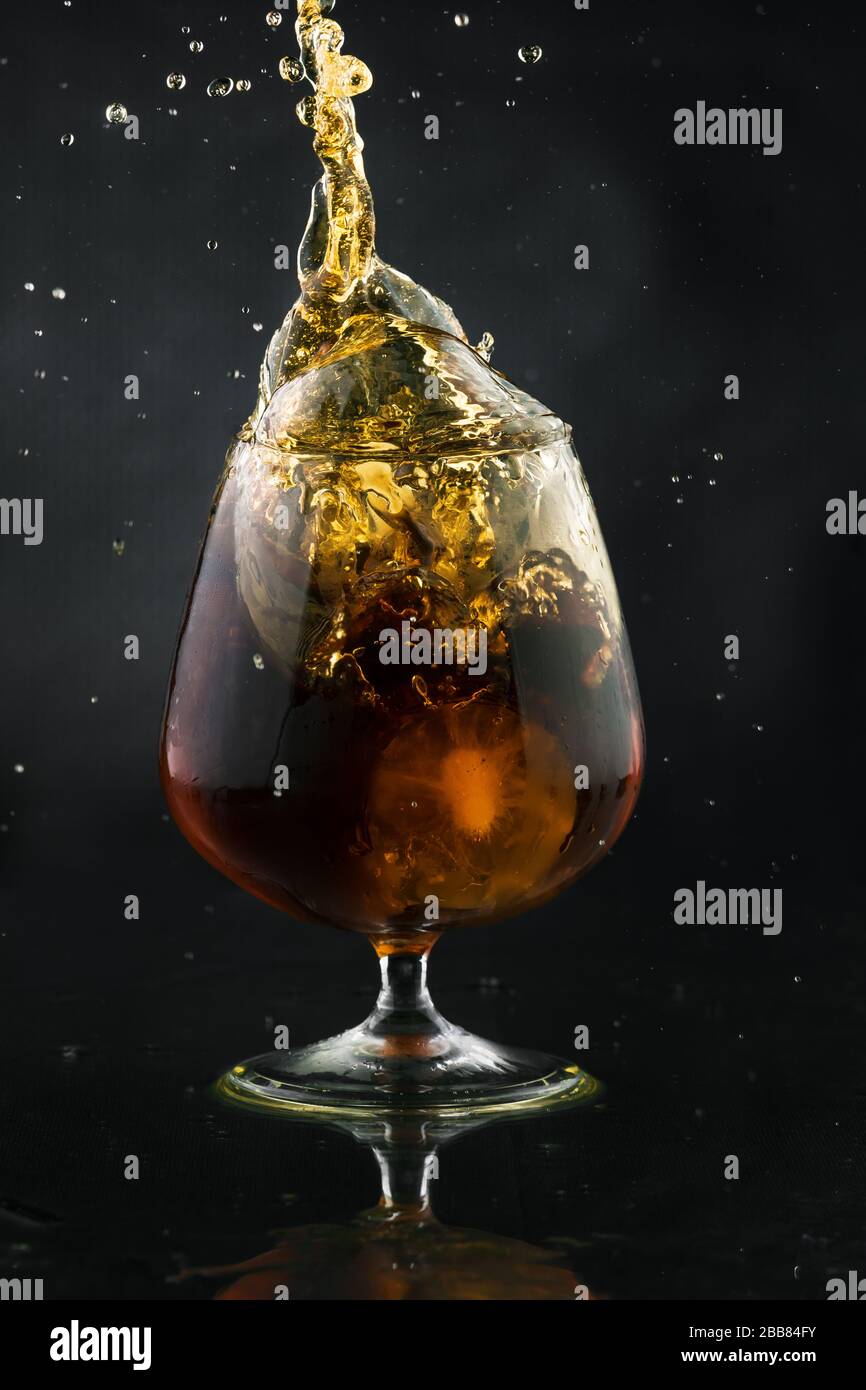 Beautiful splashes in a glass of cognac were photographed in a photo studio Stock Photo - Alamy