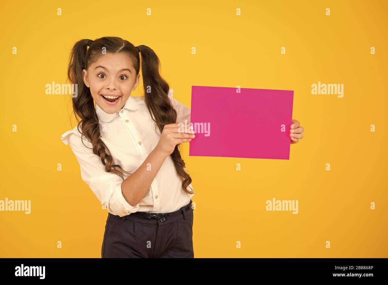 School is a happy place. Happy small child holding blank pink paper on ...
