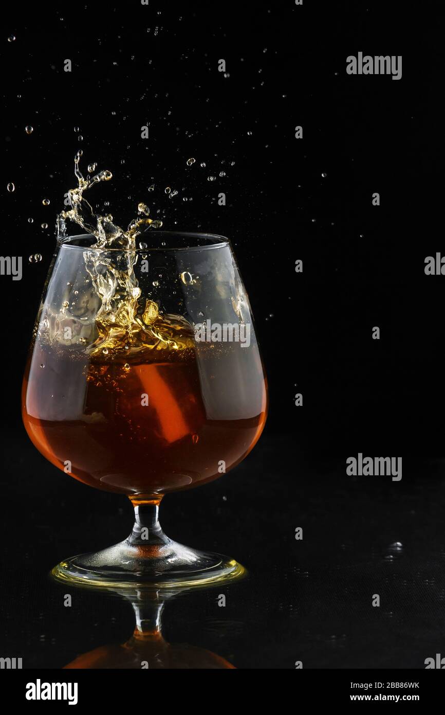 Beautiful splashes in a glass of cognac were photographed in a photo studio Stock Photo - Alamy