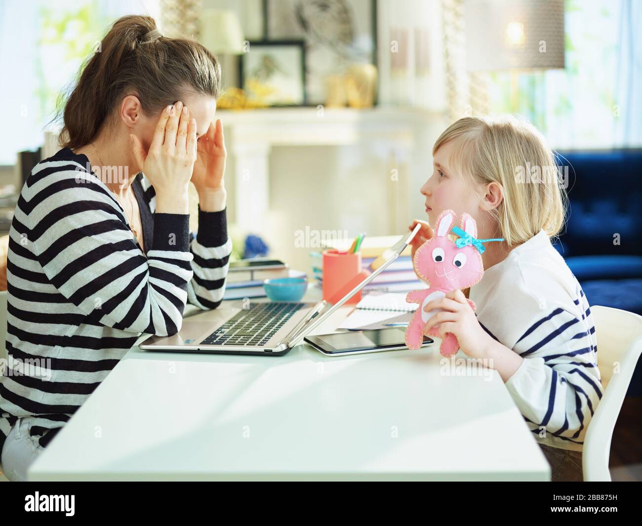 child craving attention while stressed mother busy working in home ...