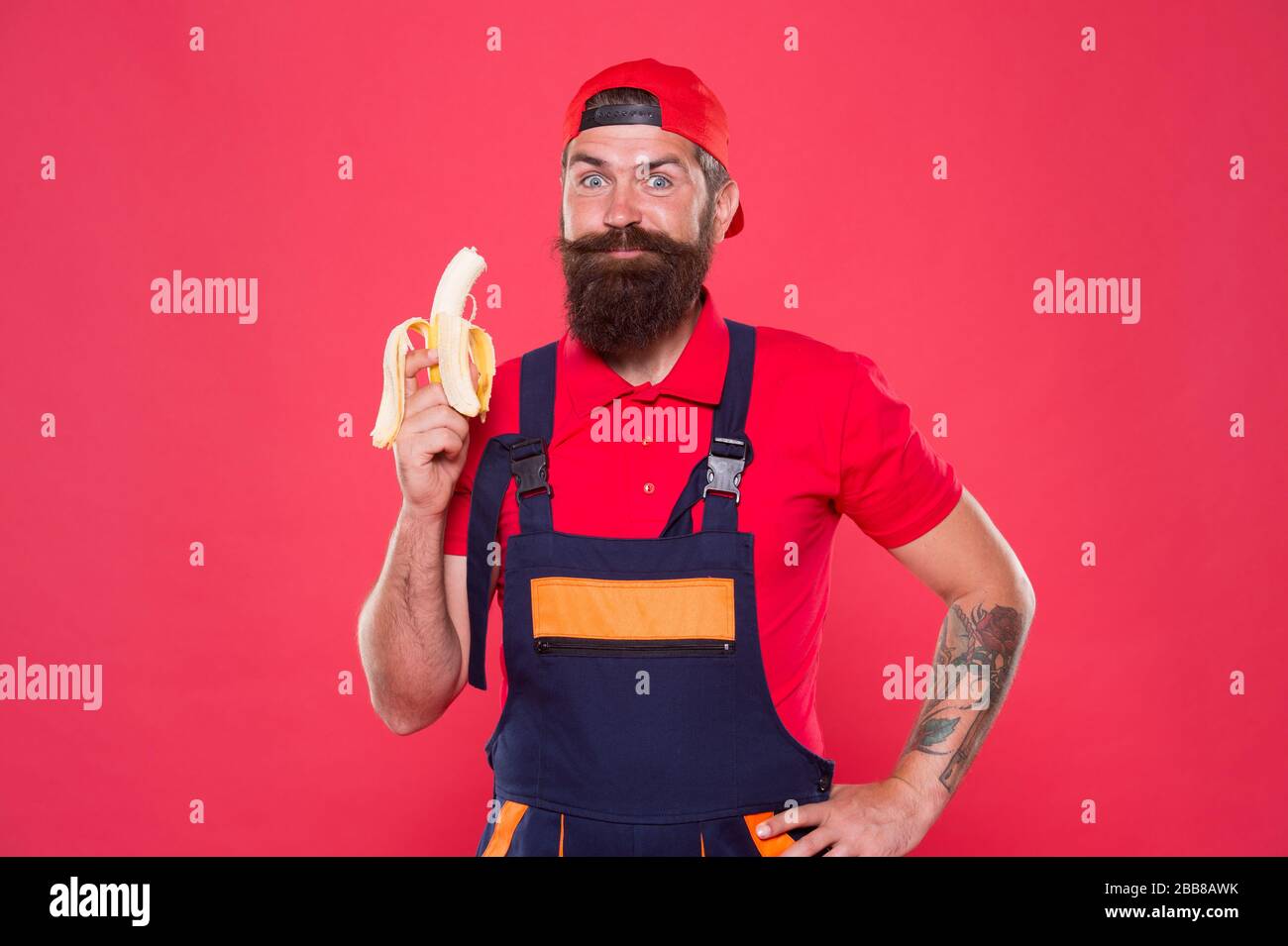 Lunch time. Bearded man in uniform and cap eating banana. Worker ...